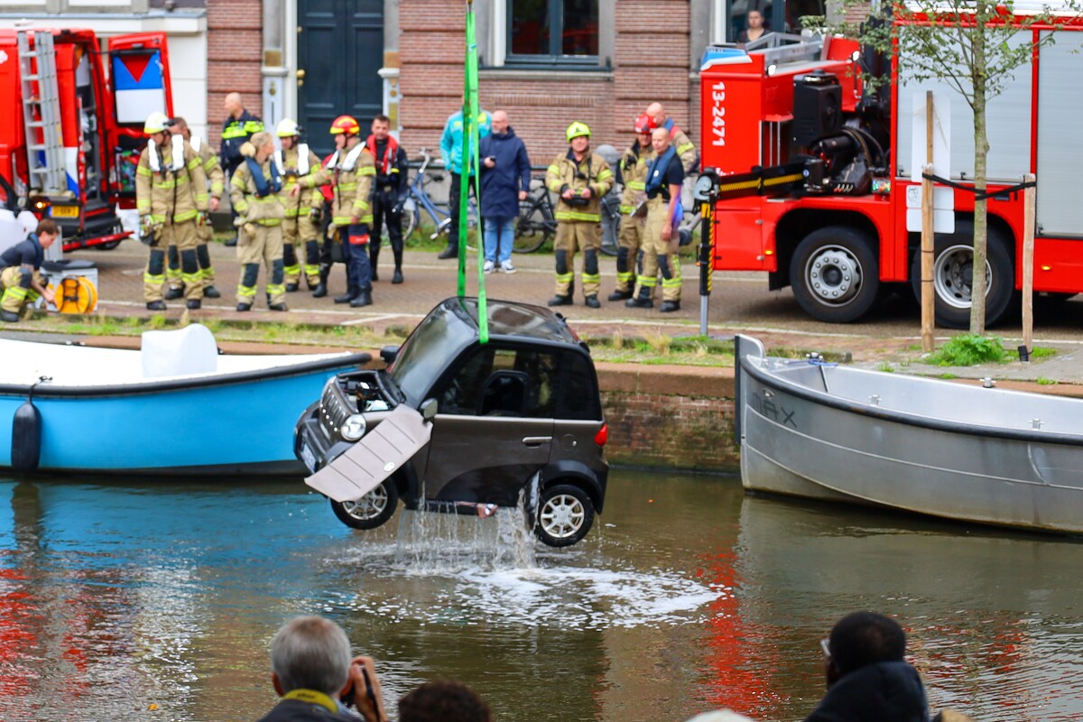 Moeder en kind rijden gracht in met Biro in Amsterdam, omstanders ...